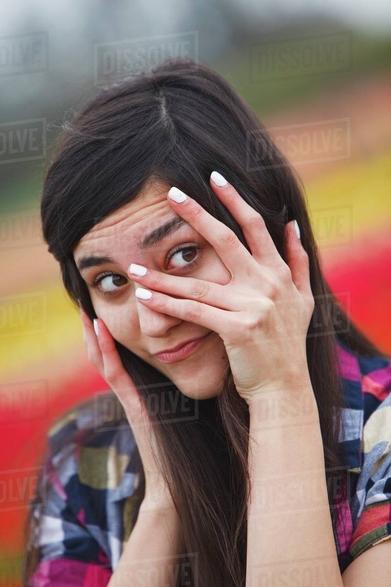 A Girl With Her Hand Over Her Face And Peeking Through Her Fingers ...