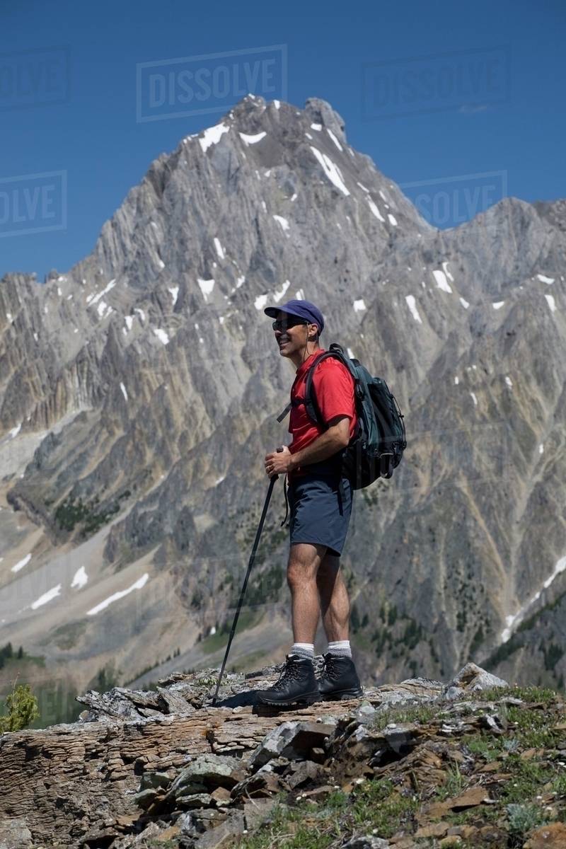 Male Hiker Standing On Top Of A Ridge With A Mountain In The Background ...