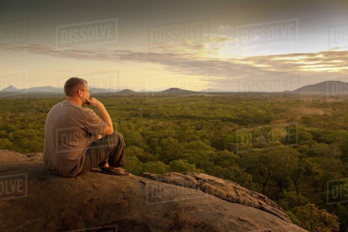 A Young Man Sitting On A Rock And Looking At The Landscape; Manica ...