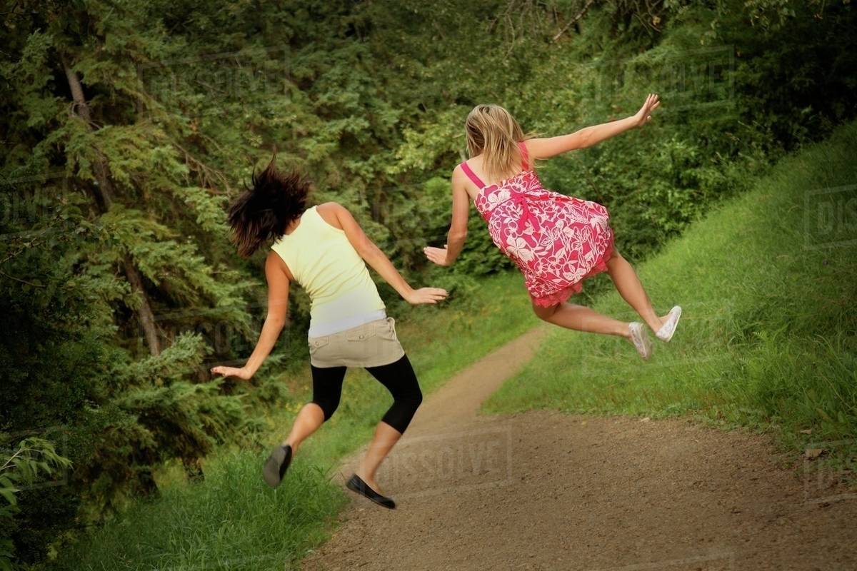 Two Teenage Girls Jumping In Park - Stock Photo - Dissolve