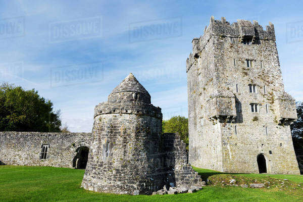 Ruins of a stone castle with stone wall and blue sky; County Galway ...