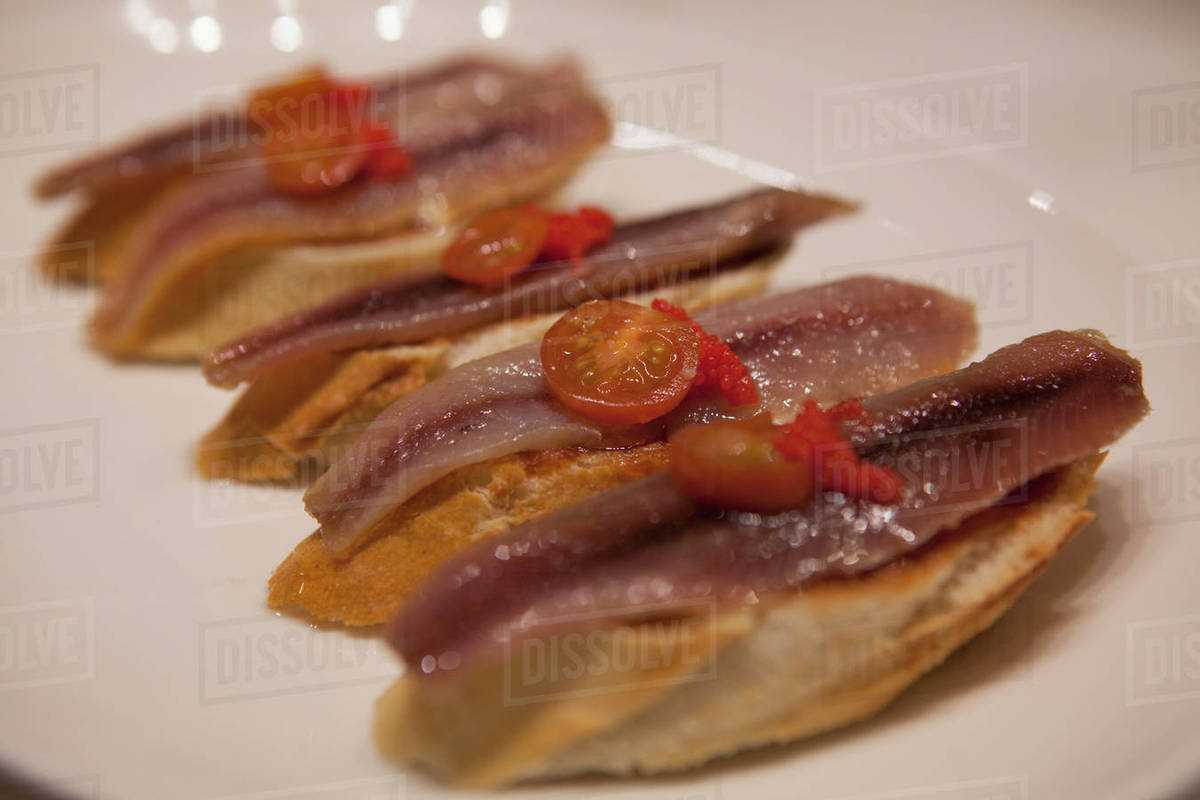 A dish of pintxos in a bar with anchovies, tomatoes and fish roe on ...