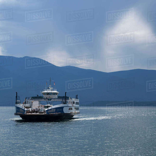 A ferry transports vehicles and people across Kootenay Lake from ...