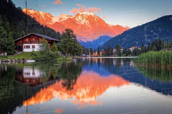 Pastel-coloured sunset glow on the mountains reflecting on Champex Lake ...