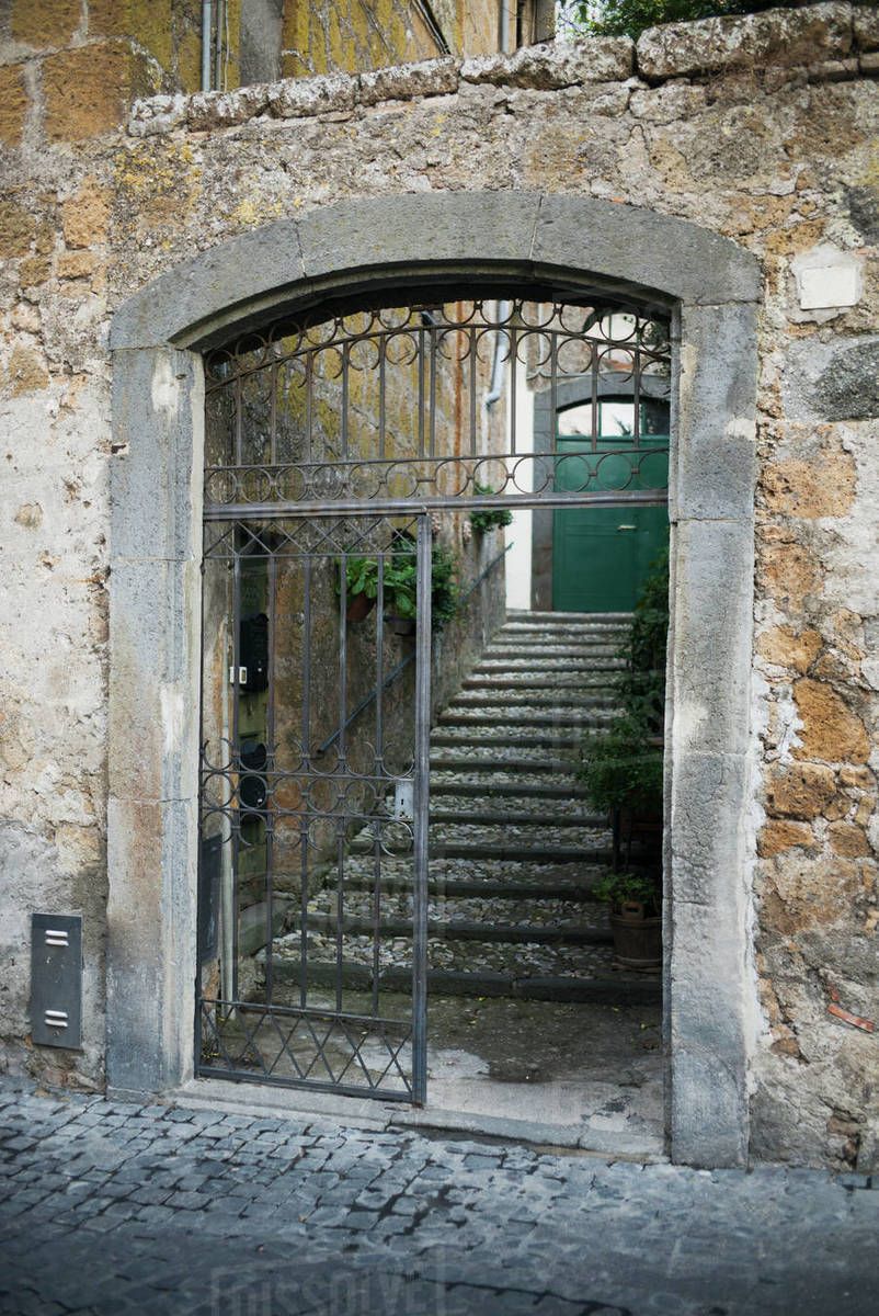 Worn And Weathered Old Stone Walls With An Open Gate Leading To Steps ...