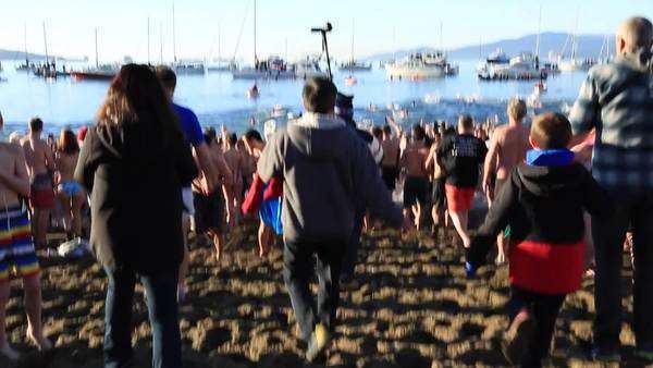 Crowd of people running with screams into cold water for polar bear ...