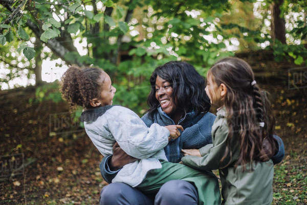Happy female child care worker playing with girls in park - Stock Photo ...