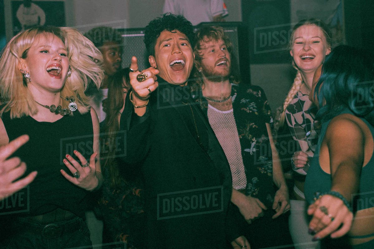 Young non-binary person dancing amidst multiracial friends enjoiying at ...