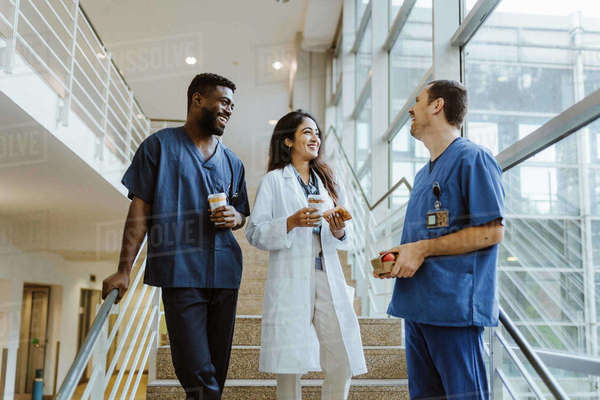 Happy multiracial healthcare workers talking while standing on ...