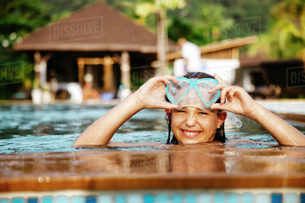 Portrait of smiling girl with swimming googles in pool at resort ...