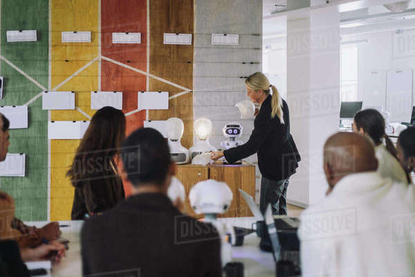 Female professor explaining students over social robot in innovation ...