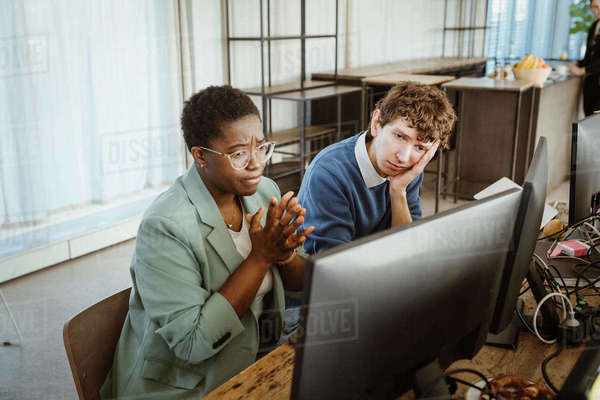 Tensed multiracial male and female programmers looking at computer ...