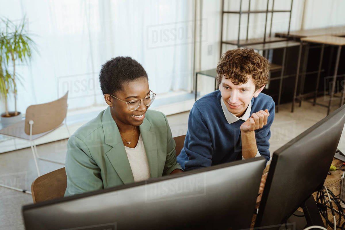 Smiling multiracial male and female programmers working on computer in ...