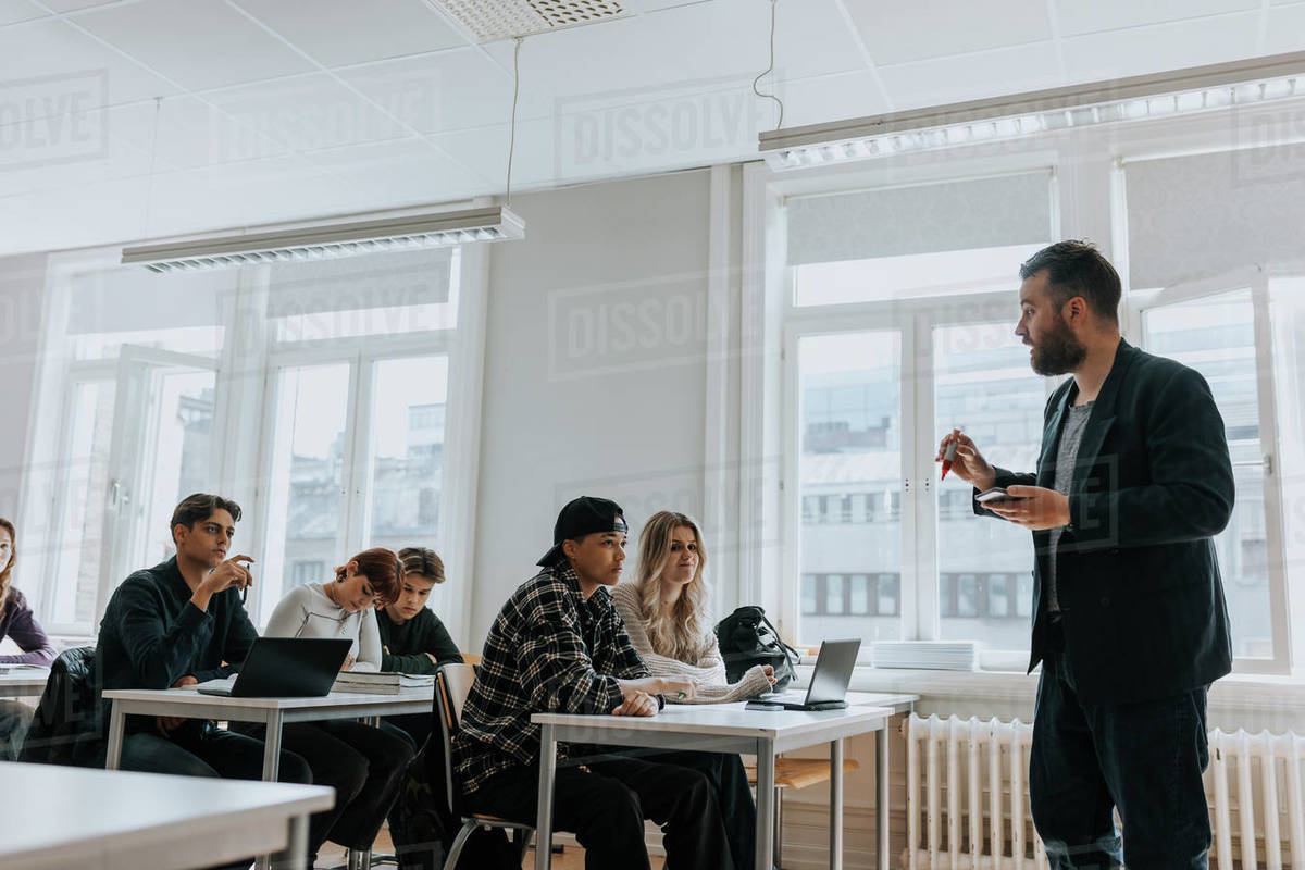 Professor teaching students sitting in classroom - Stock Photo - Dissolve