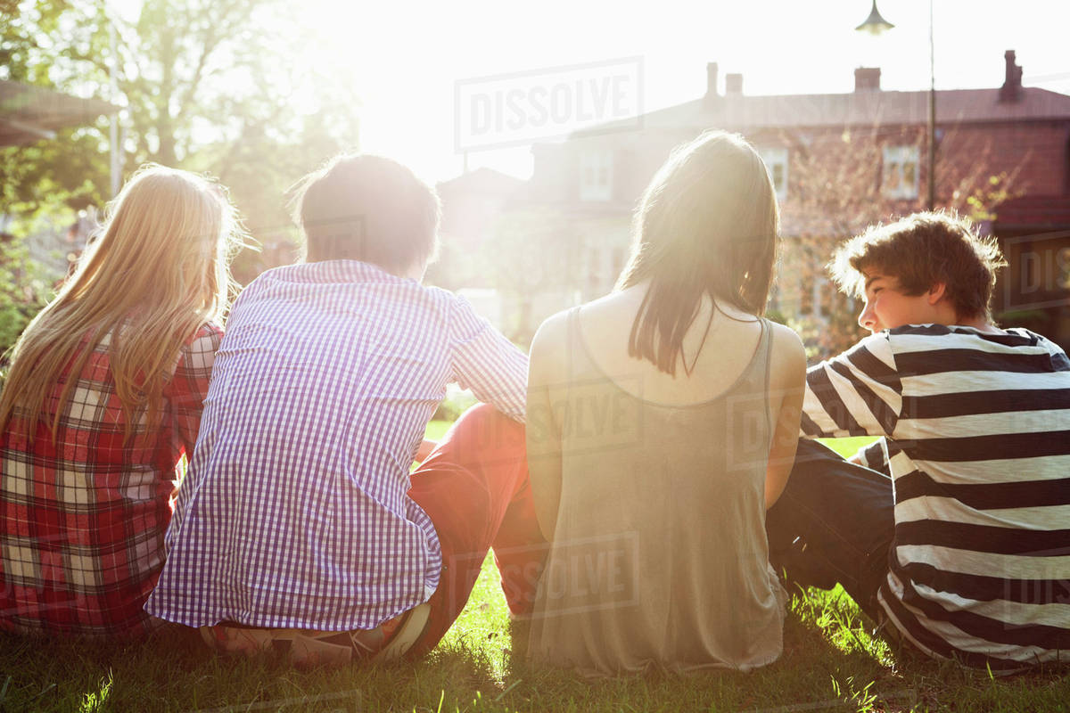 Rear view of friends sitting together on grass - Royalty-free Stock ...