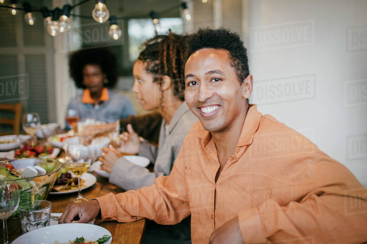 Portrait of smiling man sitting at dining table during dinner party in ...