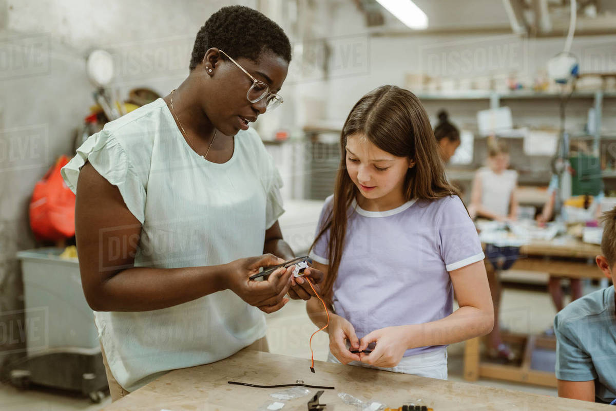 Female teacher explaining electrical part to student at technology ...