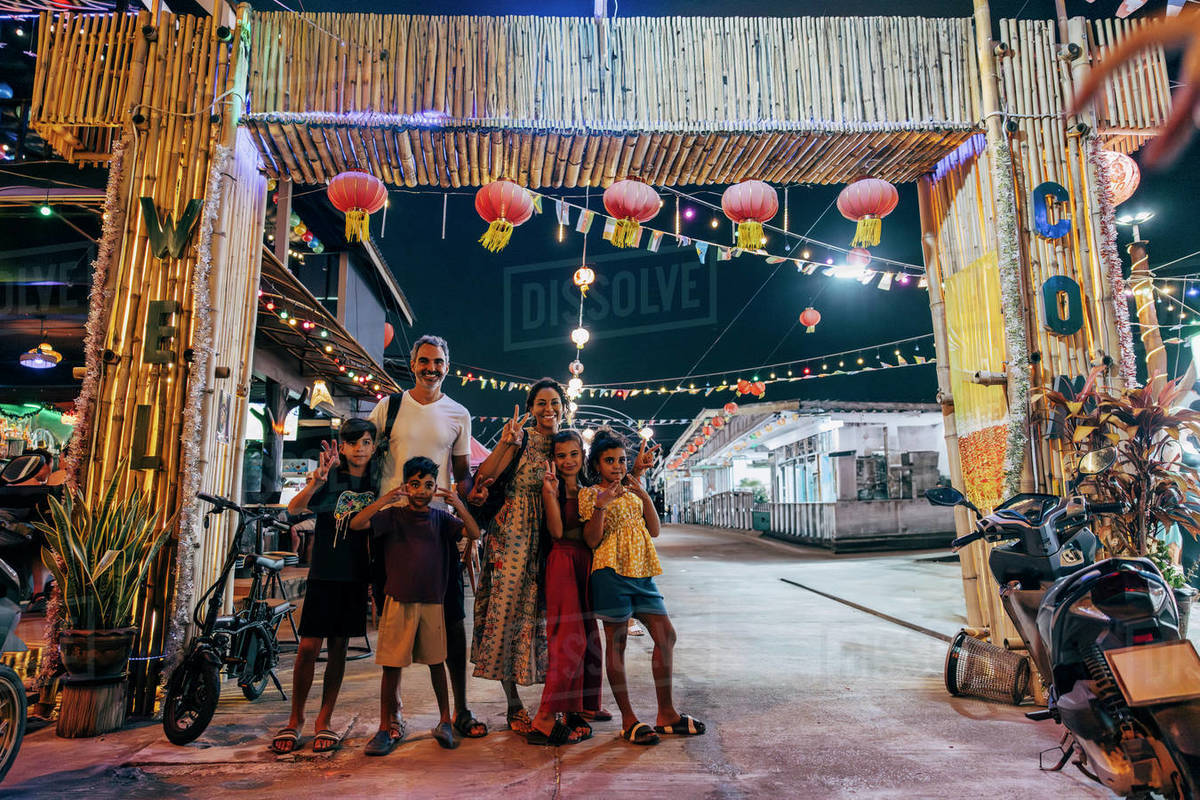 Portrait of happy family showing peace sign while standing at entrance ...