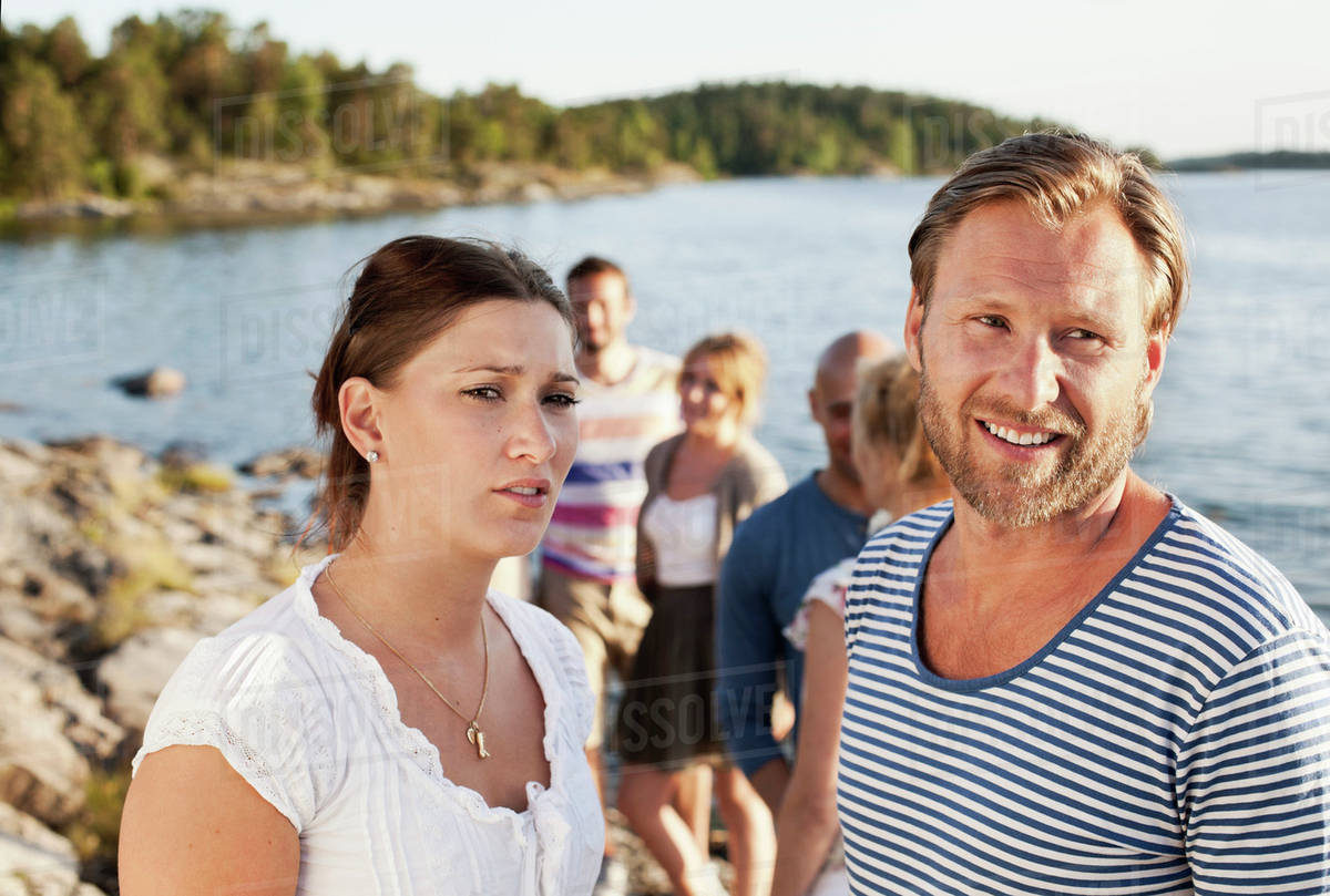 Couple looking at something with friends in background - Royalty-free ...