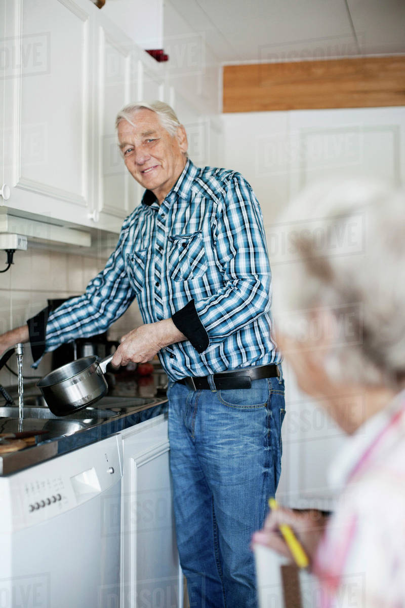 Senior man washing utensil while looking at wife - Stock Photo - Dissolve