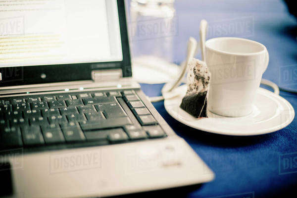 Close-up of laptop and tea cup in office - Stock Photo - Dissolve