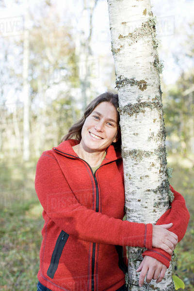 Portrait of woman hugging tree in forest - Stock Photo - Dissolve