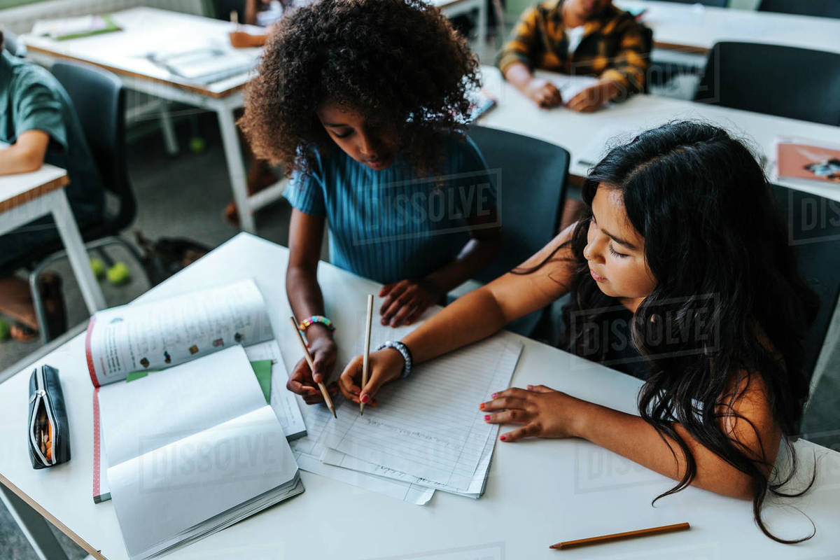 High angle view of female elementary students writing on paper while ...