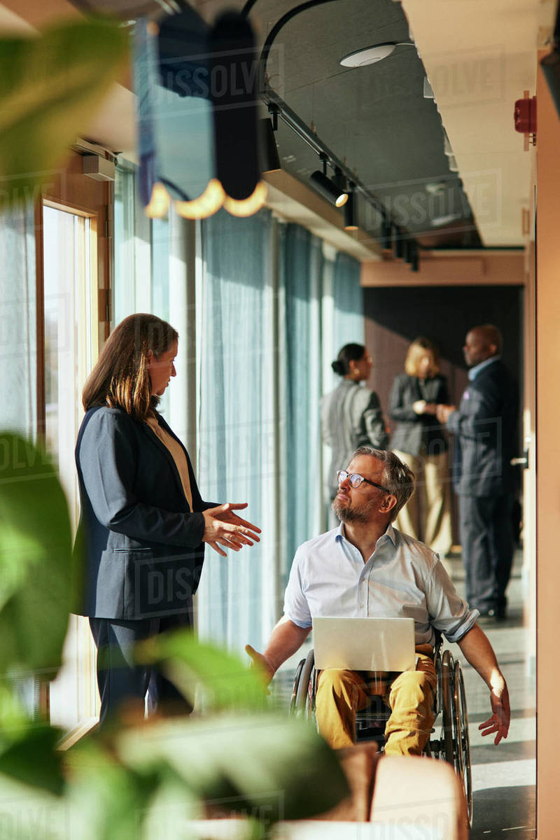 Mature female entrepreneur discussing with male coworker sitting on ...