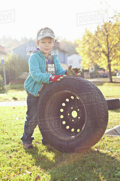 Portrait of young boy playing with vehicle tire in back yard - Stock ...