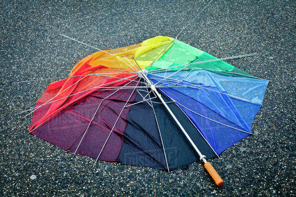 Multi colored broken umbrella on street - Stock Photo - Dissolve
