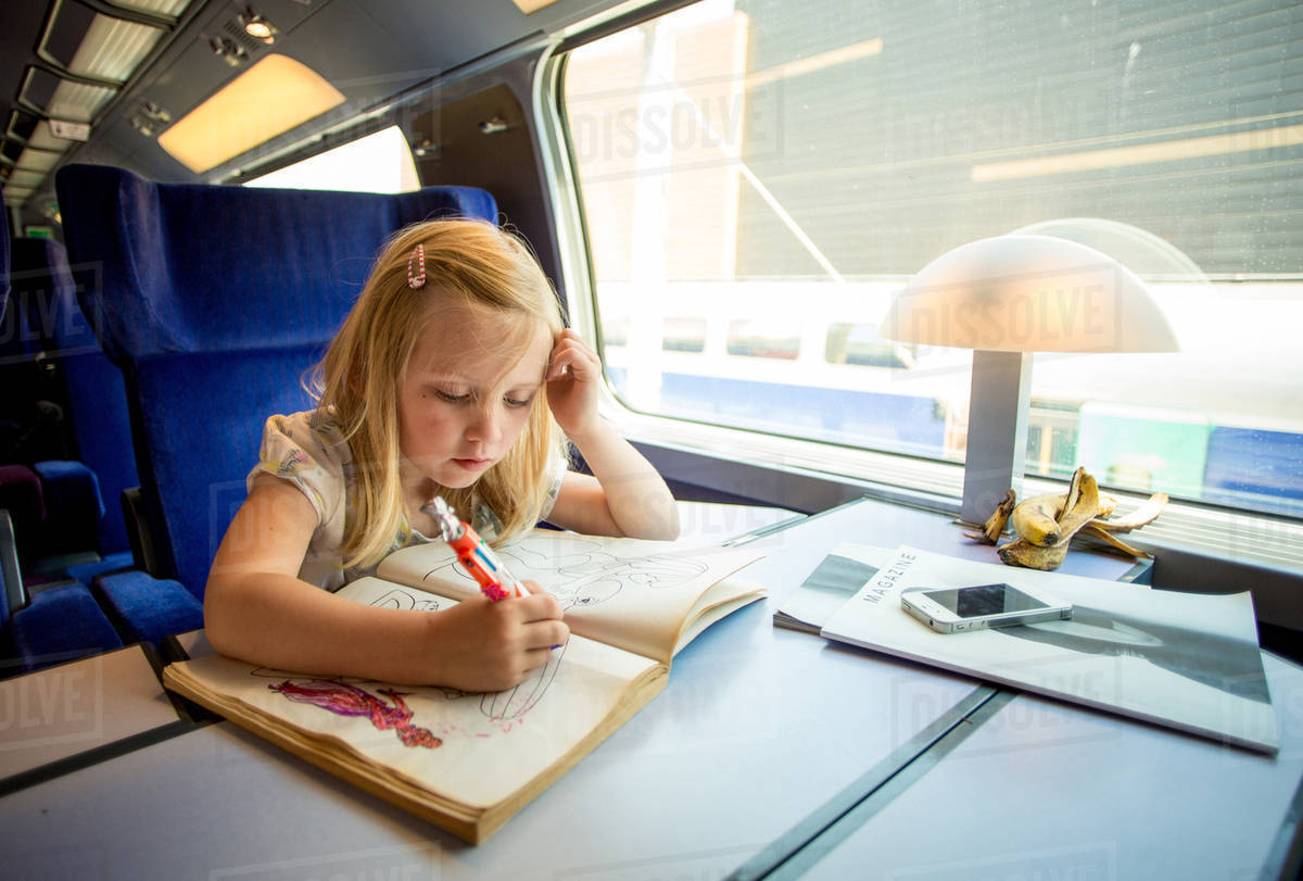 Girl drawing pictures while sitting on train's seat - Stock Photo ...
