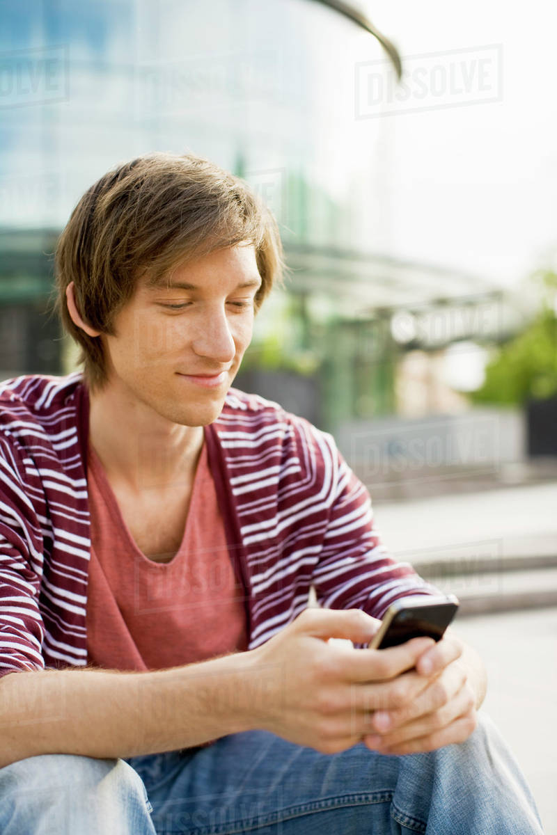 Male university student smiling while using cell phone - Royalty-free ...
