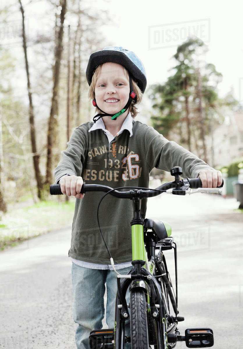 Portrait of happy boy with bicycle standing on road - Stock Photo ...
