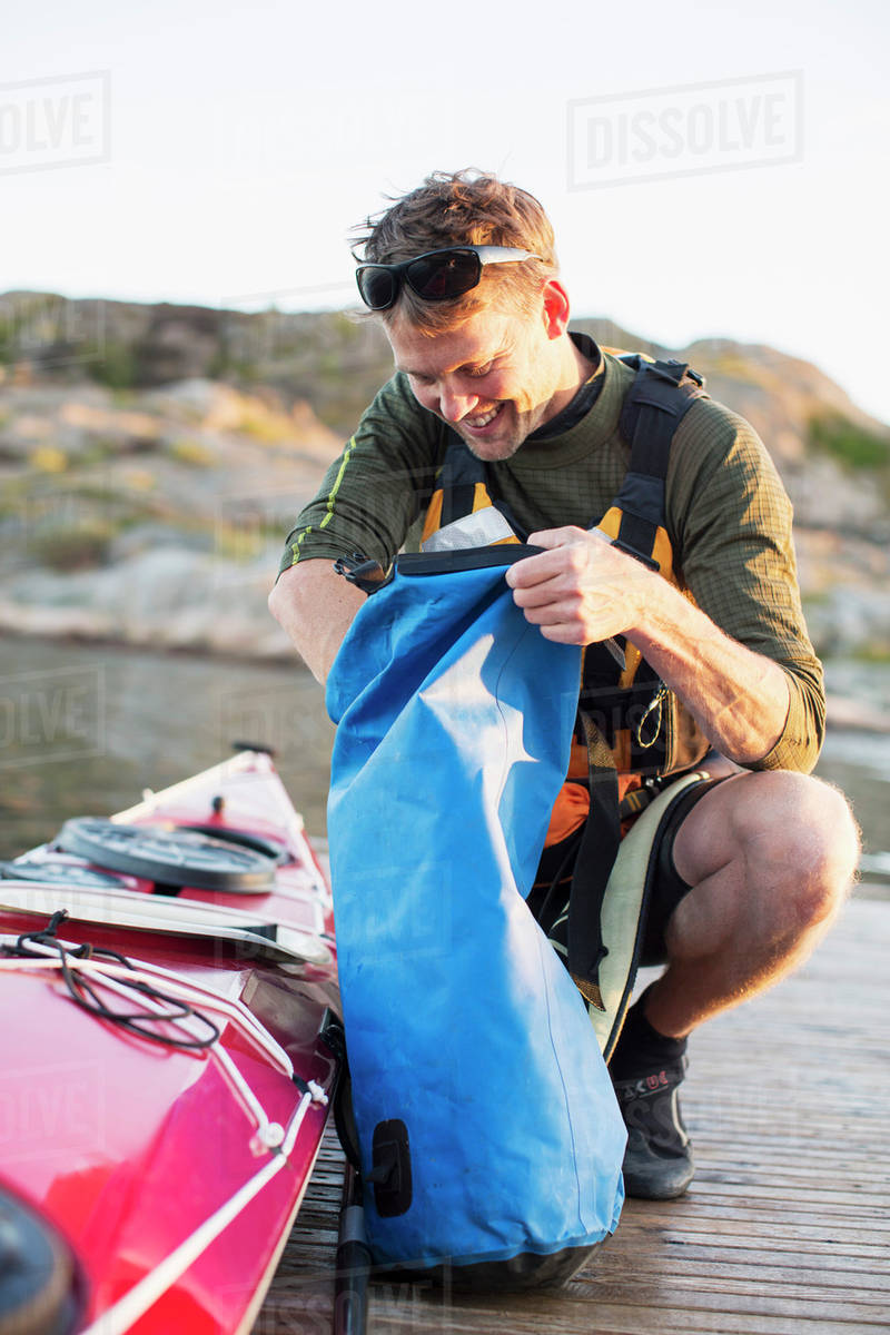 Happy man searching something in bag by kayak - Royalty-free Stock ...