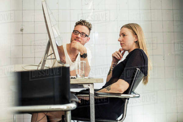 Young business people looking at computer monitor in creative office ...
