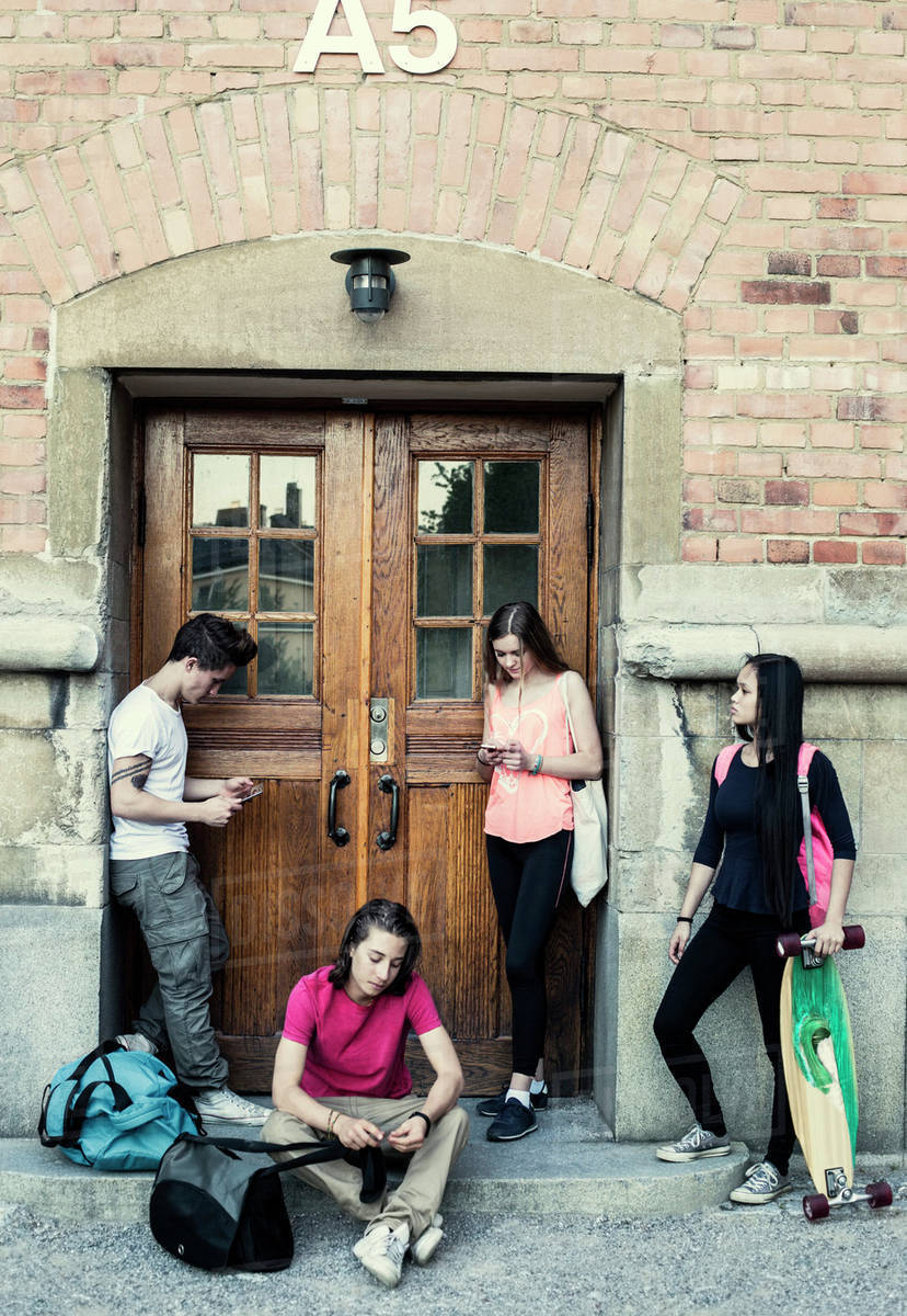 Full length of students waiting outside entrance of high school ...