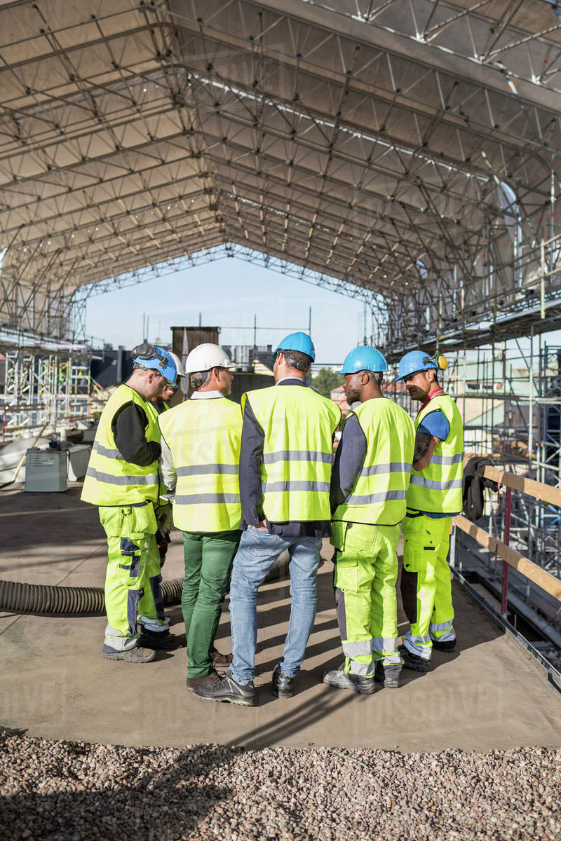 Rear view of construction workers standing at site - Stock Photo - Dissolve