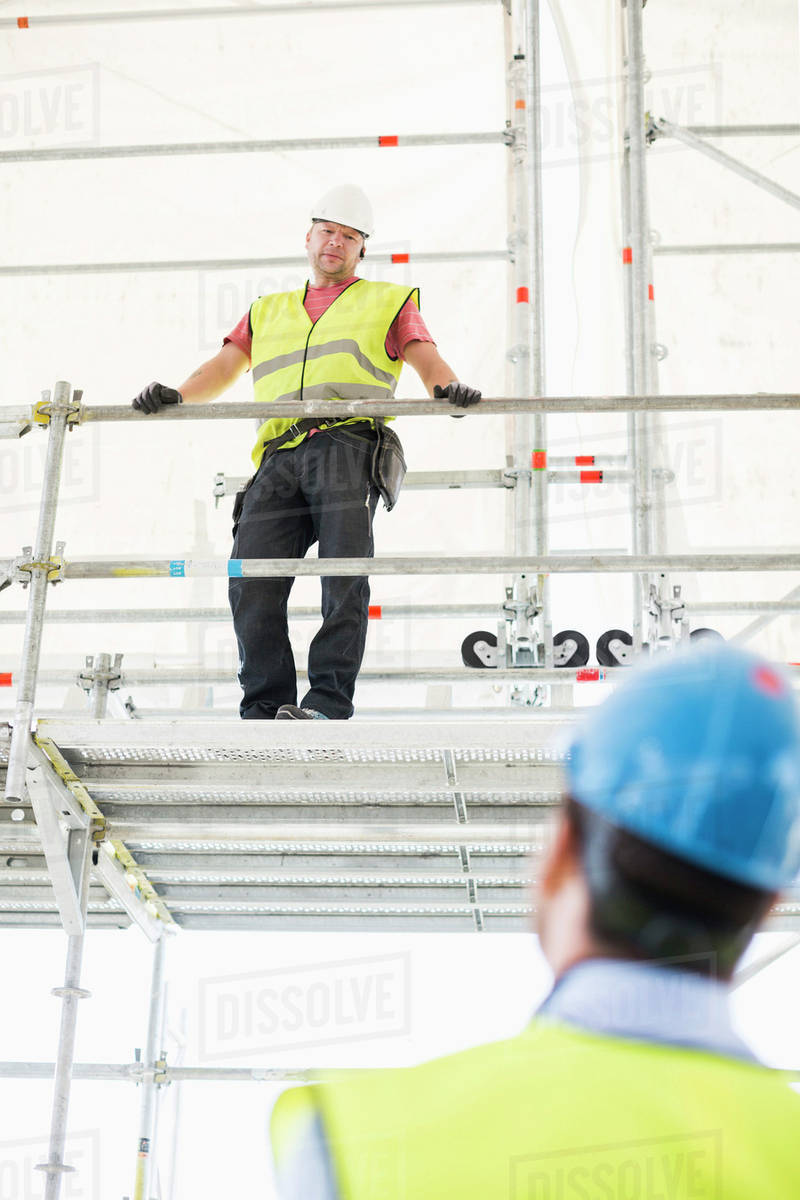 Rear view of architect looking at construction worker standing by ...