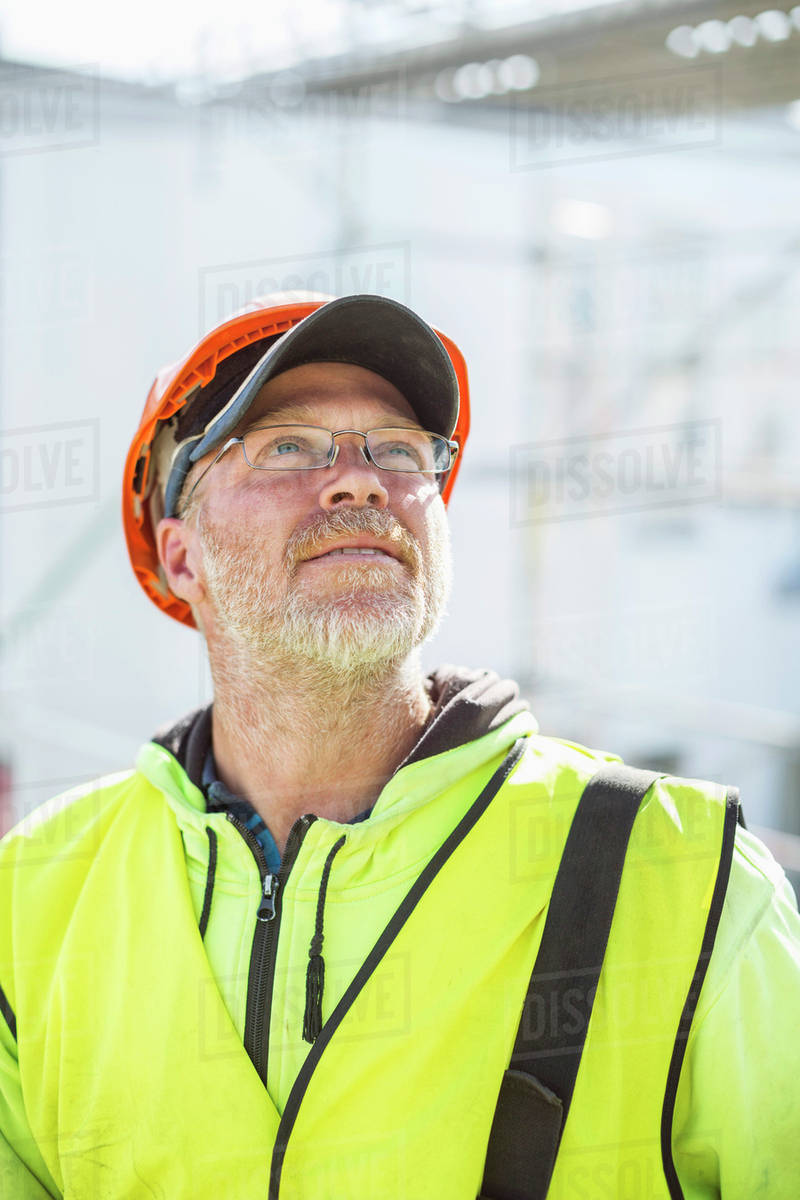 Construction worker looking up while standing at site - Royalty-free ...