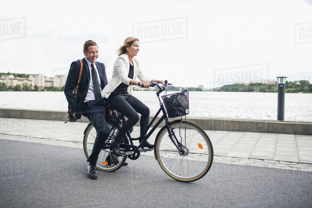 Happy business people riding on bicycle in city street - Stock Photo ...