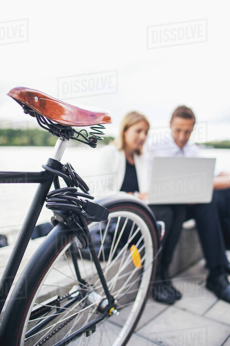 Cropped image of bicycle on sidewalk with business people working on ...