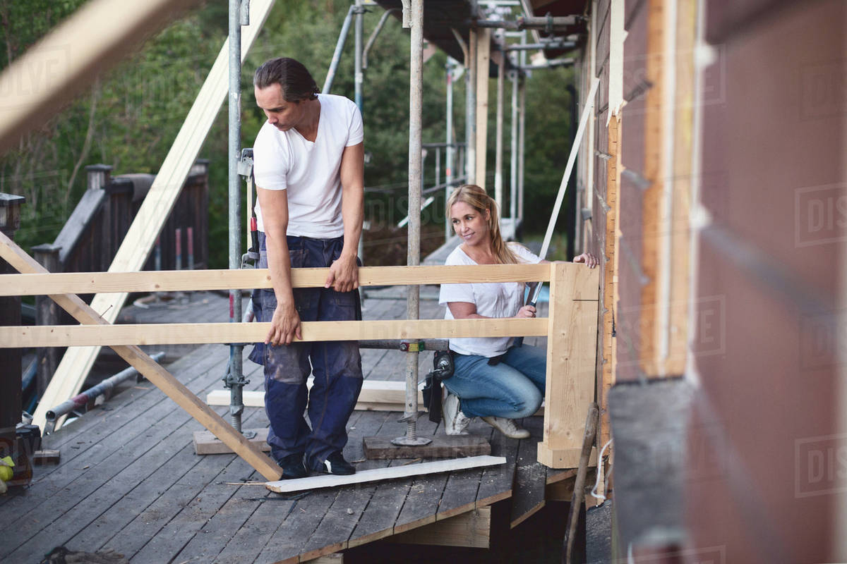 Full length of couple working on porch of house being renovated - Stock ...