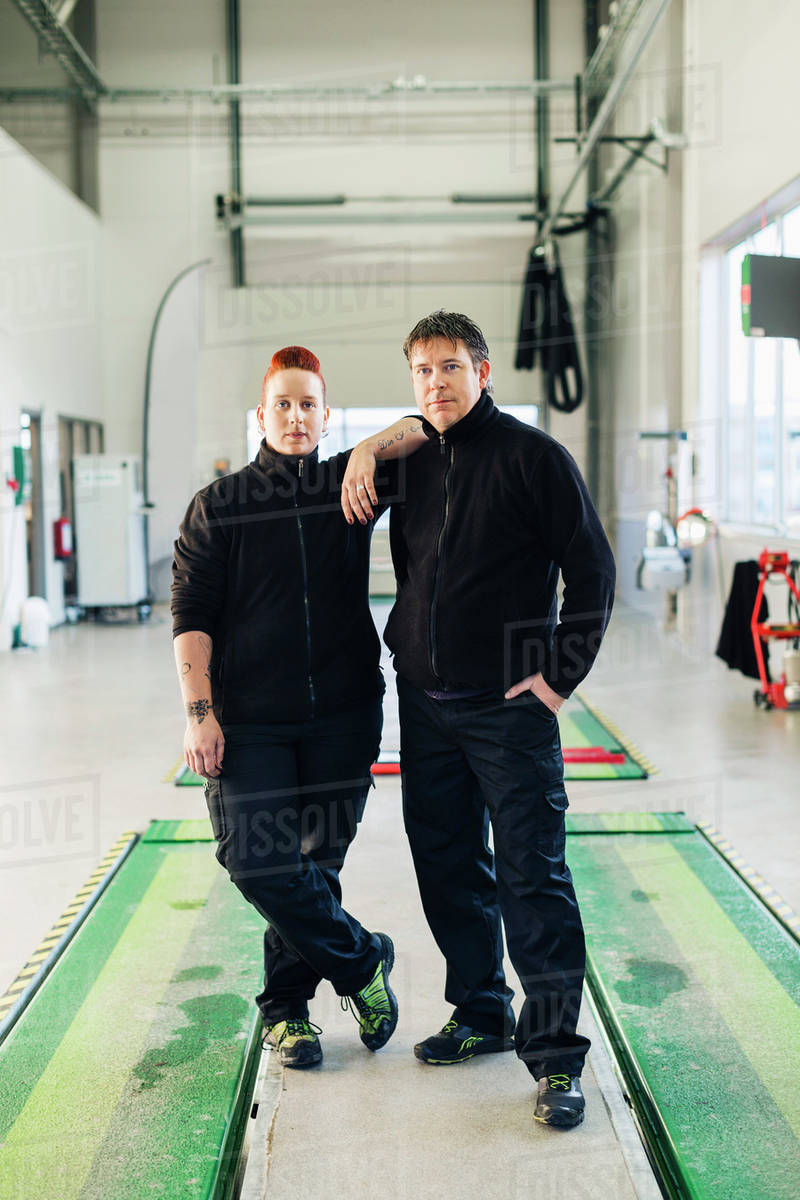 Full length portrait of confident mechanics standing in auto repair ...