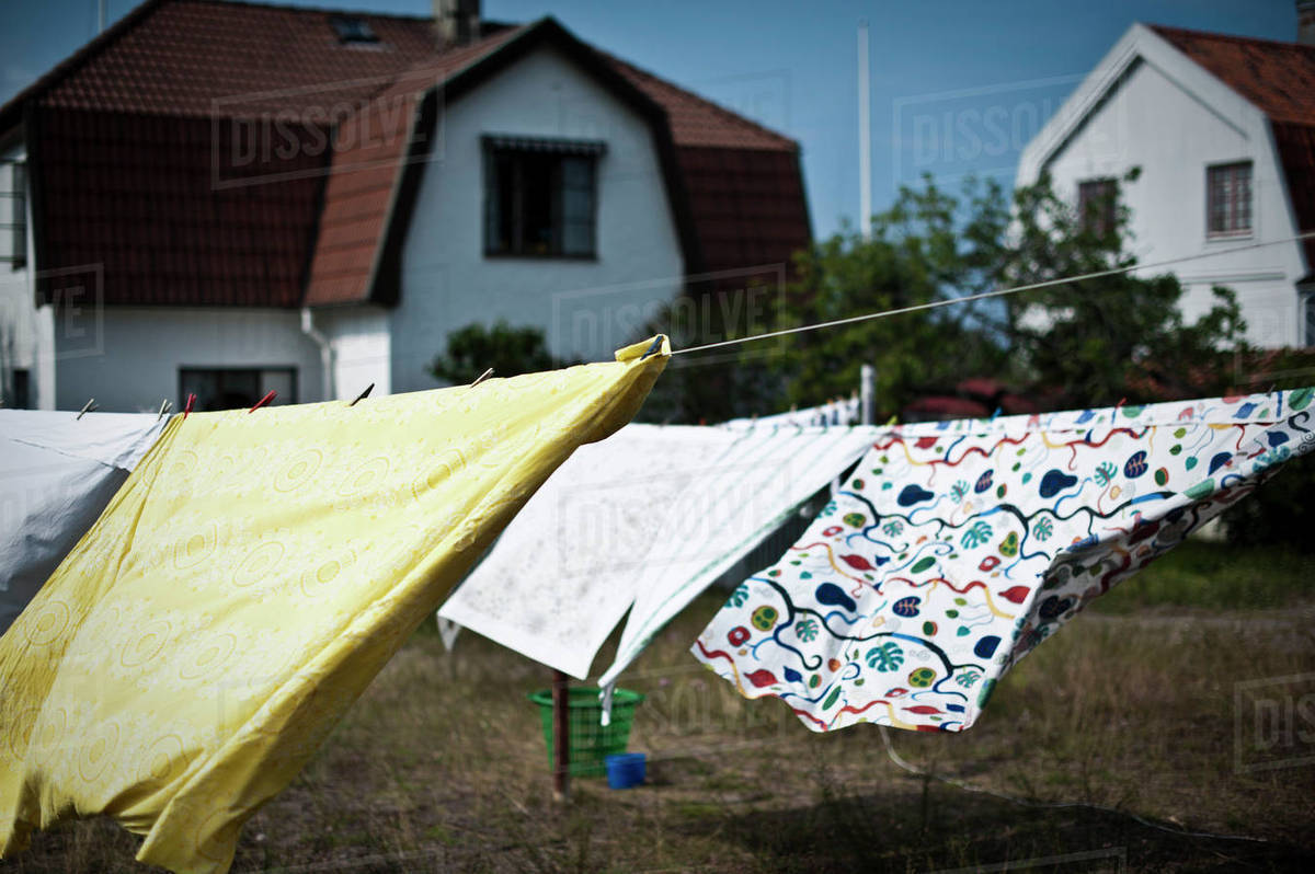 Wind blowing clothes hanging on rope in back yard - Stock Photo - Dissolve