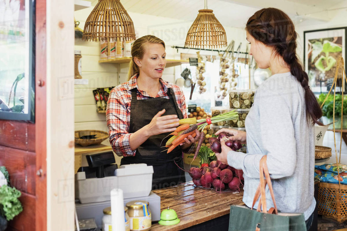Female customer talking with cashier at health food store - Royalty ...