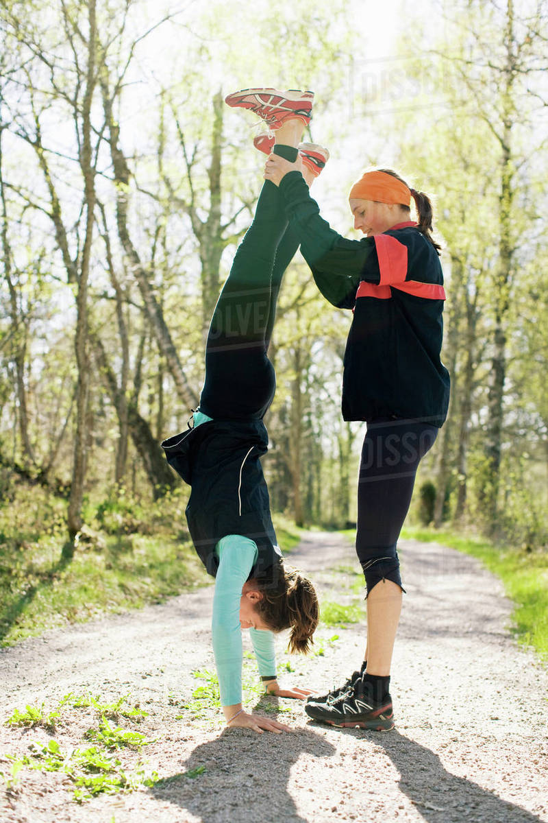 Woman helping sister doing handstand on road - Royalty-free Stock Photo ...