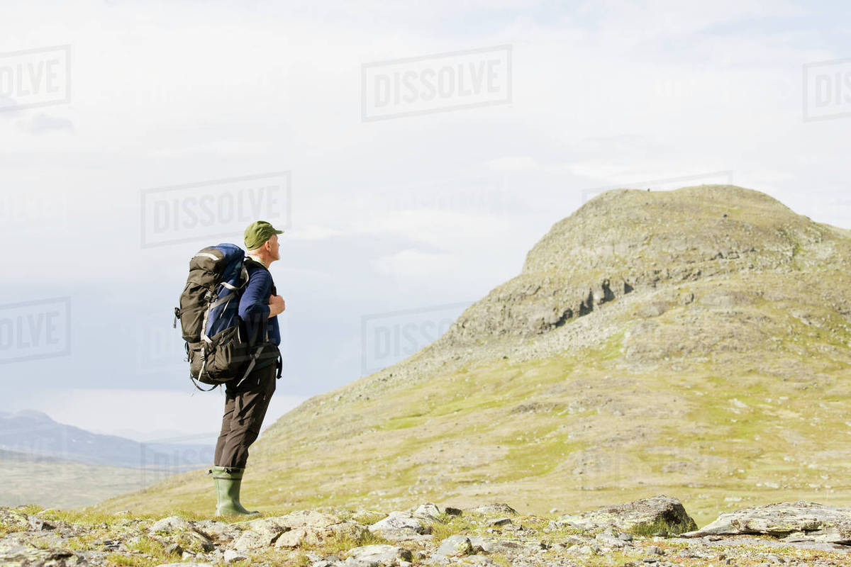 Side view of hiker standing on mountain against sky - Royalty-free ...