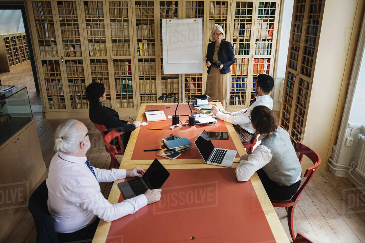 High angle view of senior lawyer giving presentation to coworkers in ...