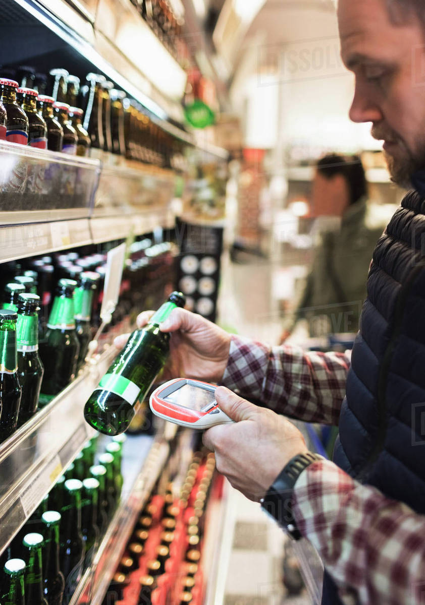 Man using bar code reader on beer bottle in supermarket - Royalty-free ...
