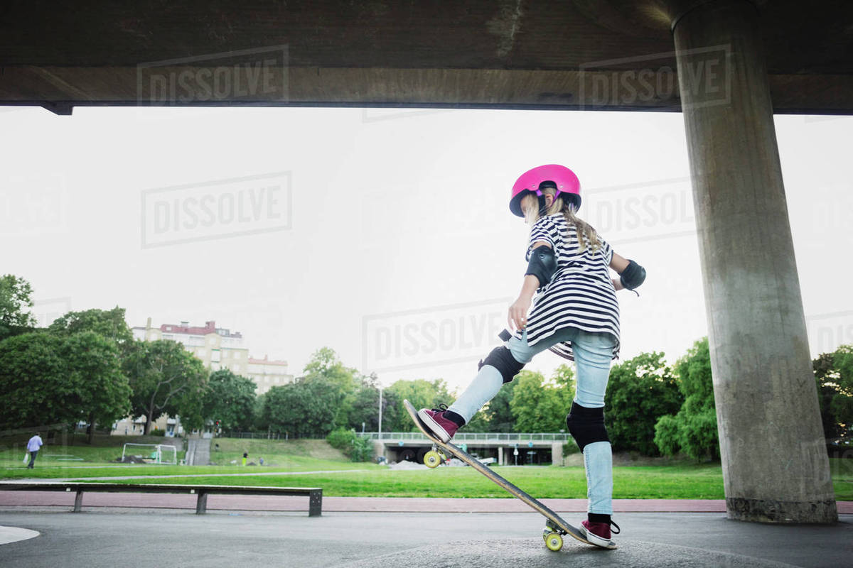 Full length of girl performing stunt with skateboard at park against ...